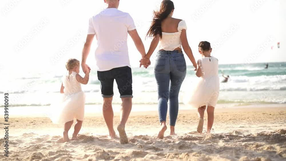 Happy family, back view. parents and two daughters on beach in summer ...