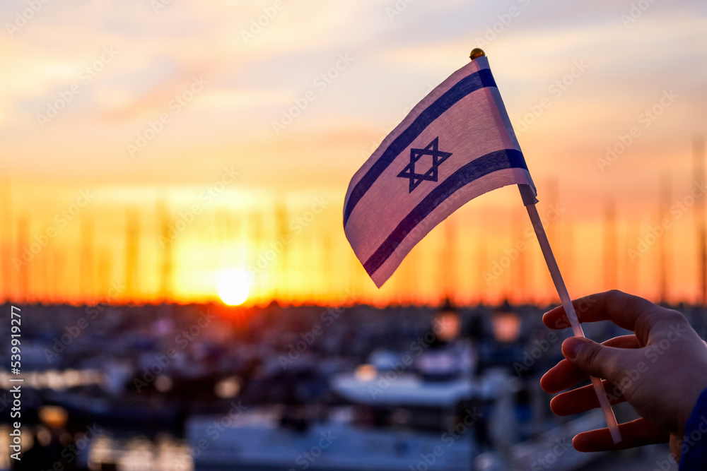Female hand holding flag of Israel against sunset sky background Stock ...