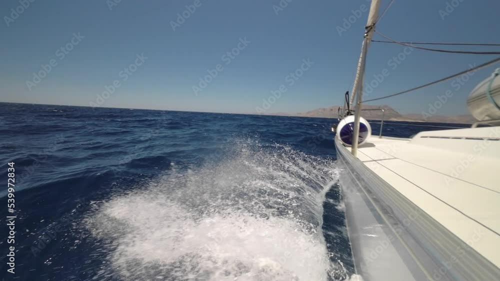 Floating sailing yacht with spread sails splitting the sea waves and an ...