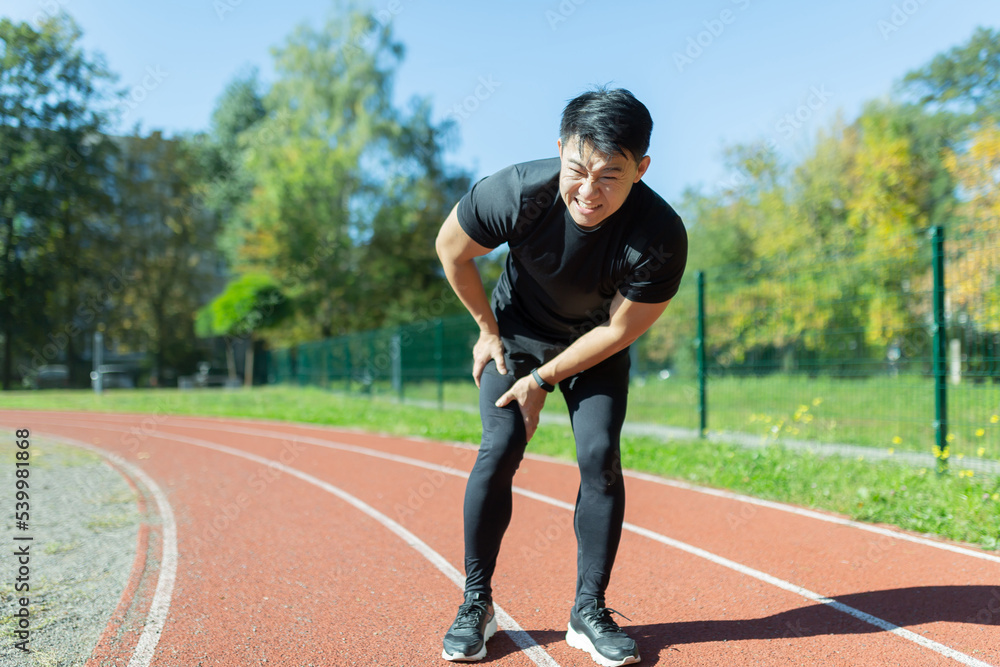 Foto de young asian runner athlete with muscle pain. Man massaging ...