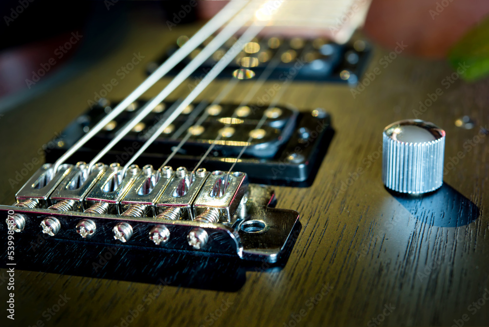 Details of the body and fretboard of an electric guitar. Stage lighting ...