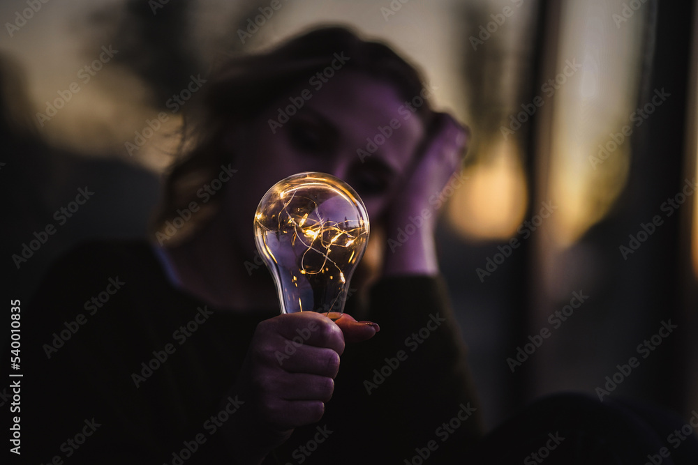 young worried female human holding bright shining lightbulb in her ...