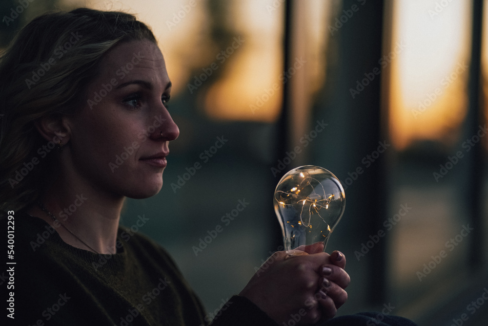 young worried female human holding bright shining lightbulb in her ...