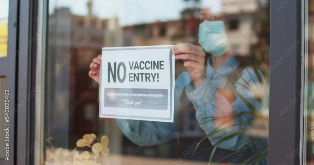 Caucasian business owner woman wearing face mask attaching sign on the ...