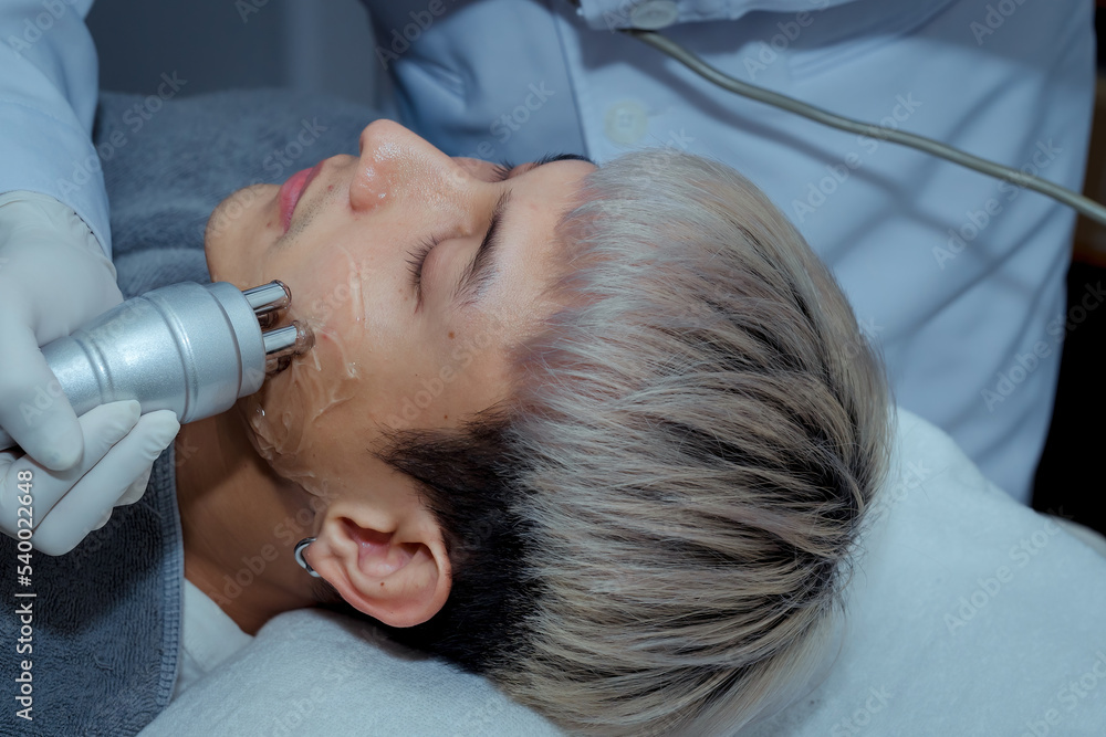 RF lifting procedure on the face of a young man in a spa salon ...