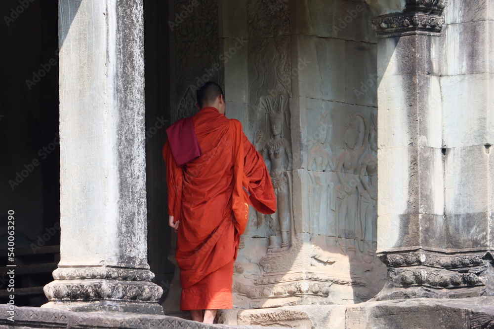 Cambodia. Angkor Wat temple. A monk looks at a bas-relief of an Apsara ...