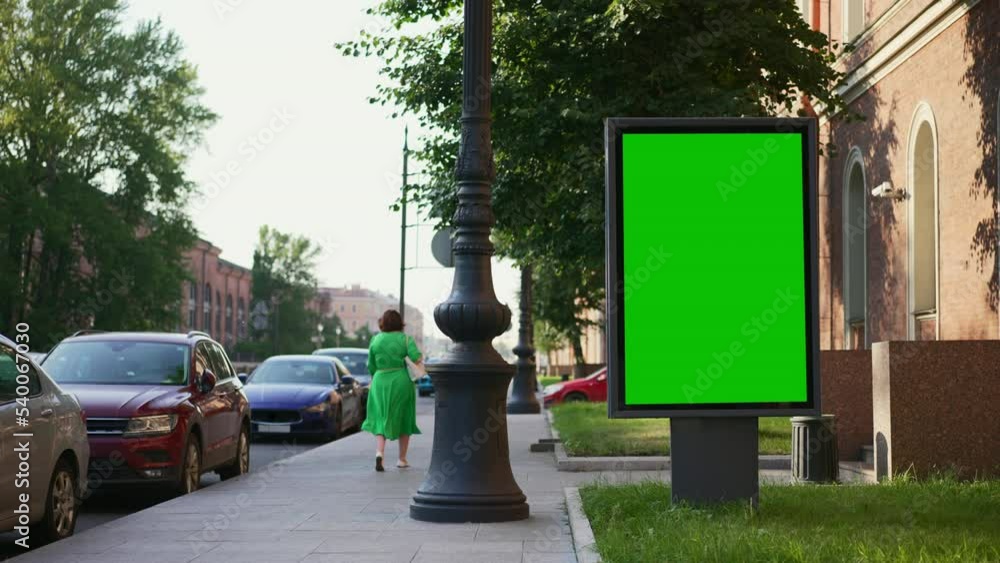 4k Green billboard stands and woman walks along city street spbd ...
