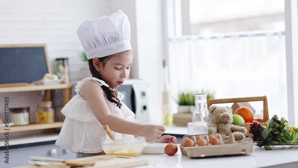 toddler girl is learning to cook bread in the kitchen with her mom with ...