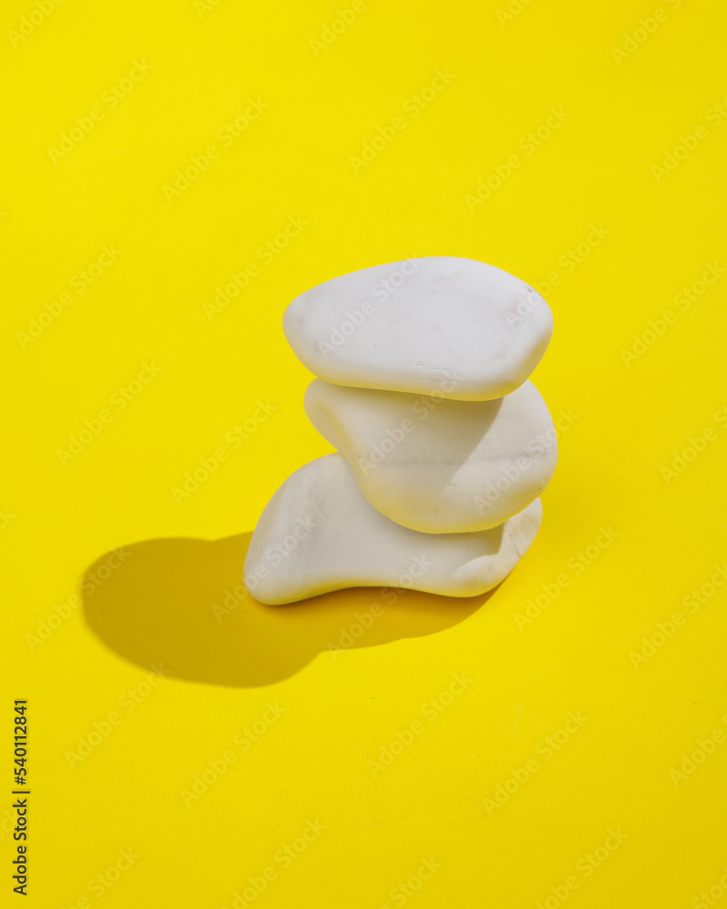 Creative layout with stack of pebbles. Bright yellow background with ...