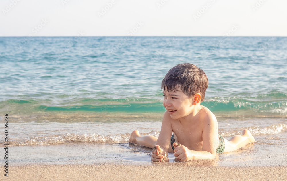 little boy kid having fun in sea ocean water lying on sands beach ...
