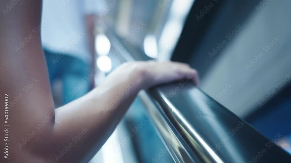 Close up female passenger hand holding on the escalator handrail. Asian ...