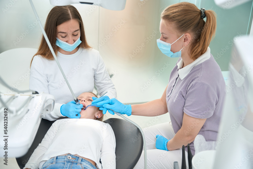Pedodontist treating tooth decay in preteen girl assisted by nurse ...