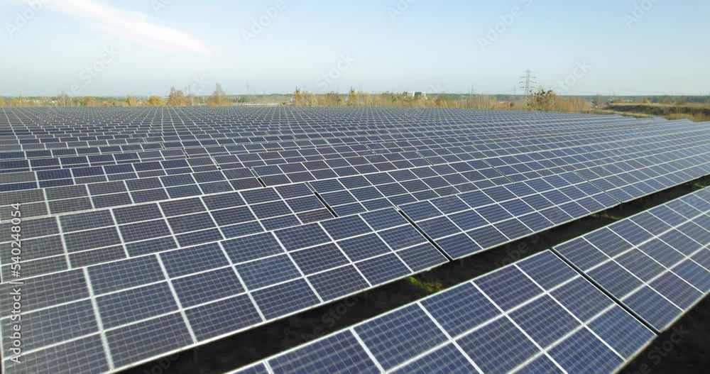 Solar panels stand in a row in the green fields. Renewable ecological ...