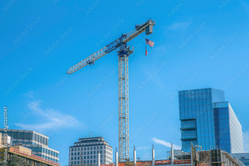 Austin, Texas- Tall tower crane with hanging US flags above the under ...