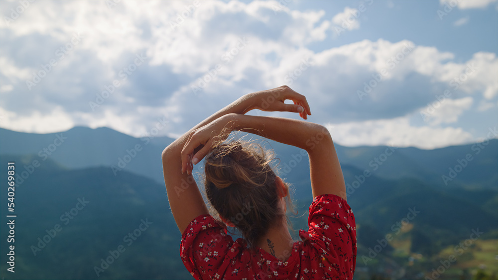 Girl standing raising hands in mountains close up. Back view woman on ...