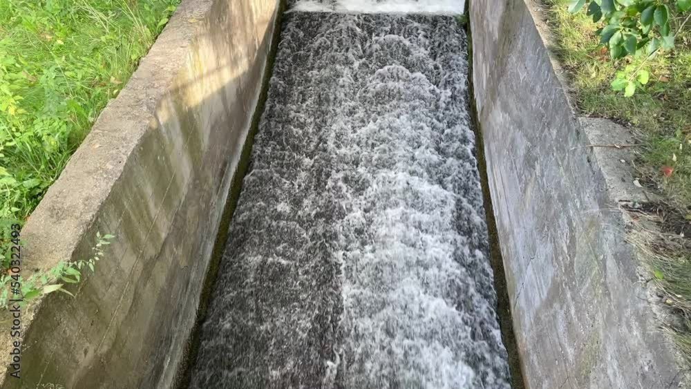Wideo Stock: Water flows violently through a concrete drainage channel ...