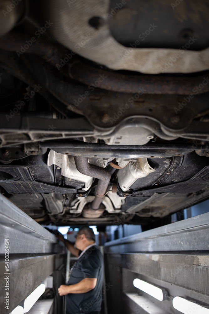 Car mechanic under a car in a repair shop/car garage (shallow DOF/color ...