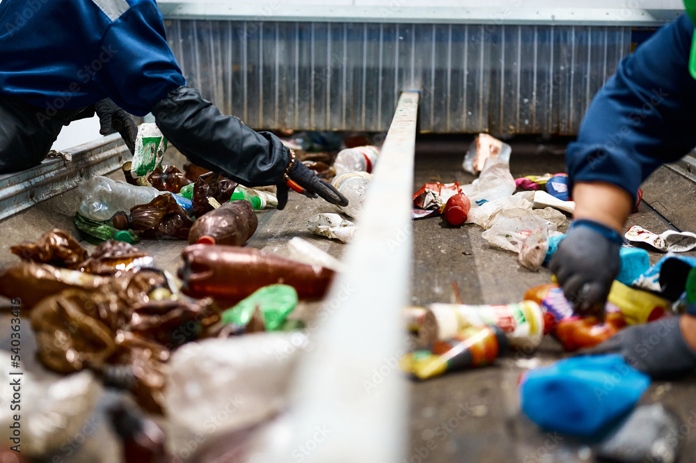 Plakát Worker sorts trash on conveyor belt at waste recycling plant ...