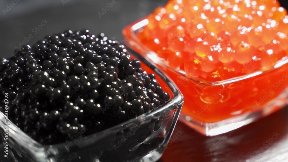 Red and black caviar in two identical transparent glass bowls on a ...