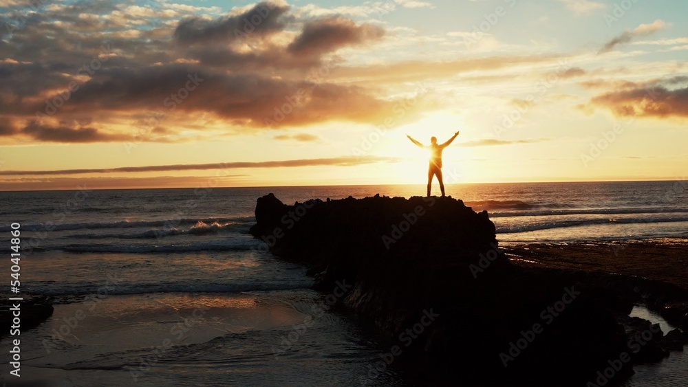 Human with raised hands looks to the sun over horizon in morning while ...