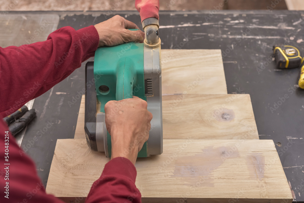 Using a hand-held sanding machine or belt sander to level the surface ...