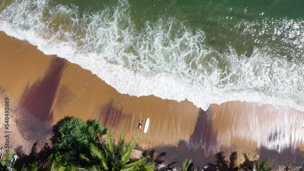 Lonely tired surfer man lying in STAR pose on the sandy beach washed by ...