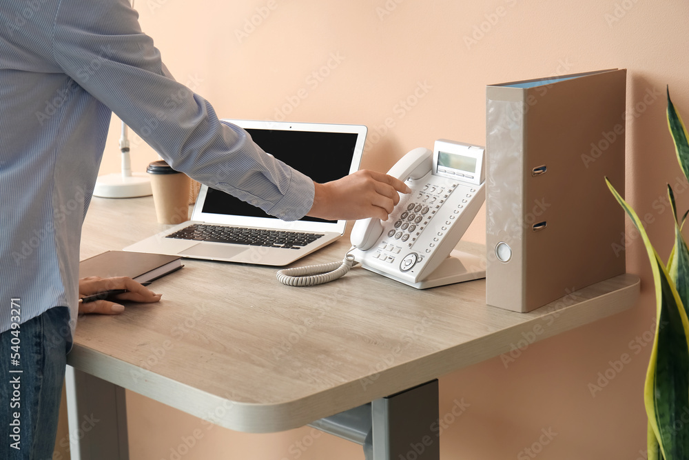 Woman taking landline phone handset on wooden standing desk Stock Photo ...