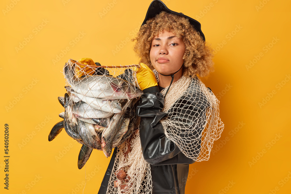 Boastful female angler holds net full of fish looks self assured ...