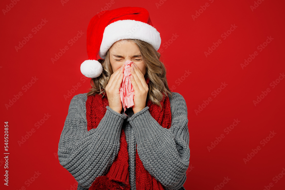 Young woman 20s wearing grey sweater scarf hat blowing nose use napkin ...