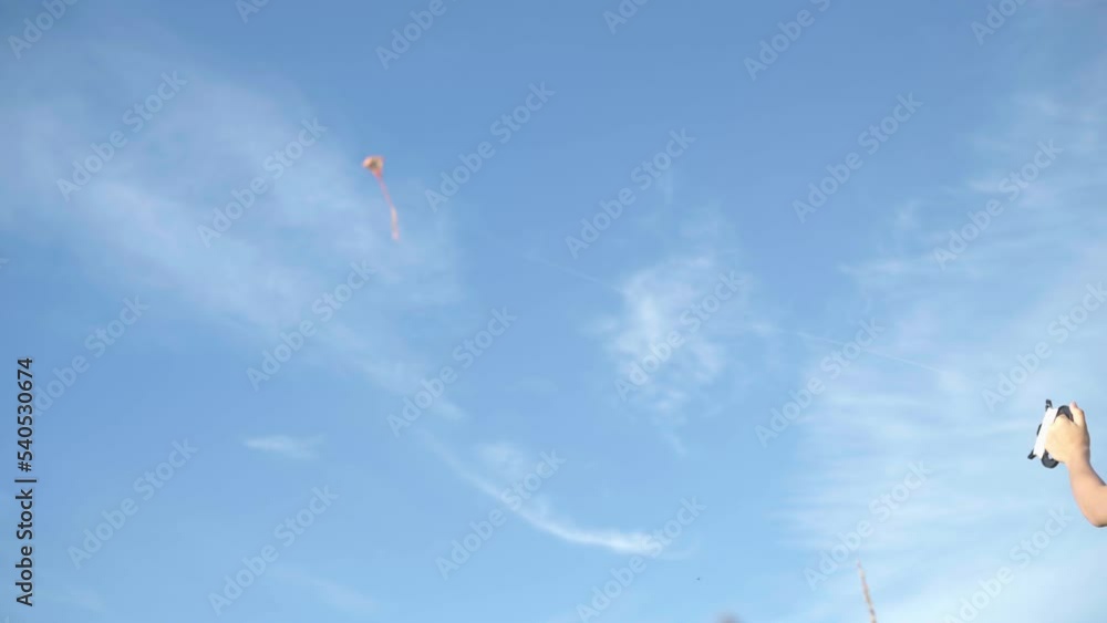 4K little girl launching flying kite in bright blue sky pulling on long ...