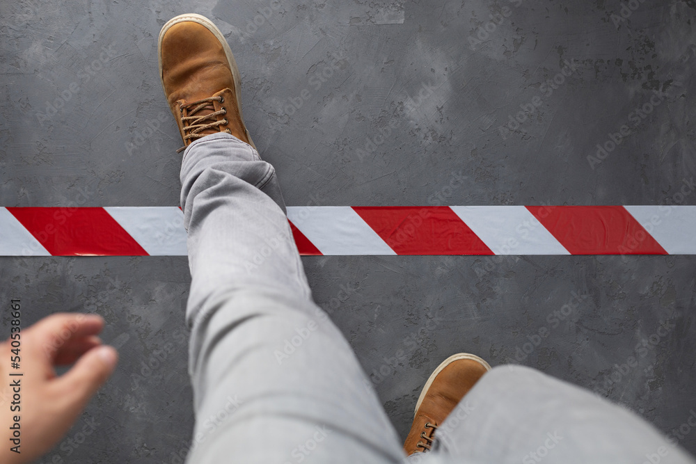 Man stepping over signal warning tape at cement floor background ...