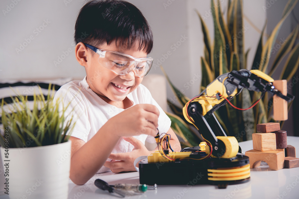 Happy Asian little kid boy using screwdriver to fixes screws robotic ...