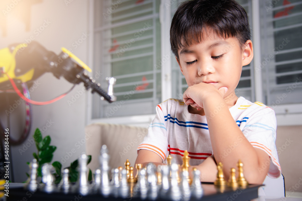 Asian little boy thinking and wait robot arm playing chess, STEM ...