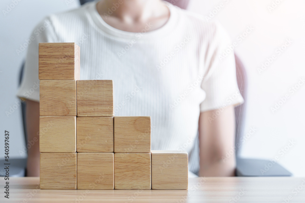 Woman hand placing wood block on the building. Leadership, Business ...