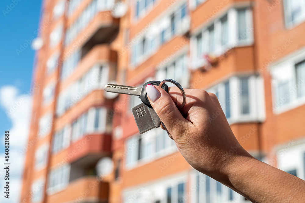 Strong male hand holding house keys and key ring in house shape close ...