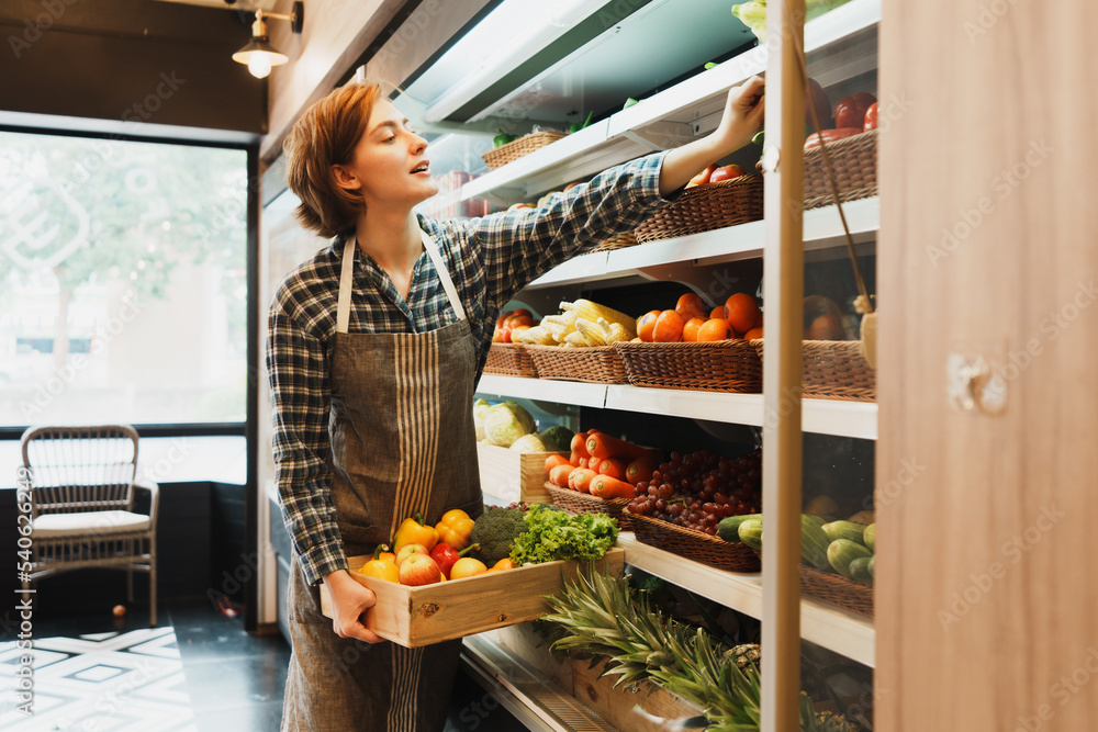 Caucasian young adult employee is working on adding the stock of fruit ...