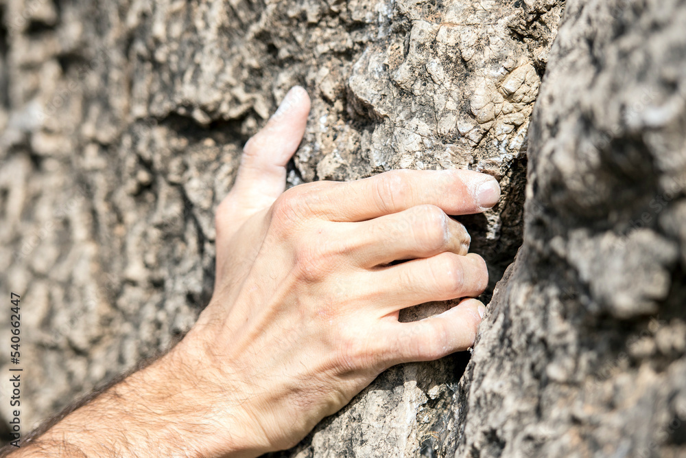 Detail of the fingers in tension of a climber clinging to a rock with ...