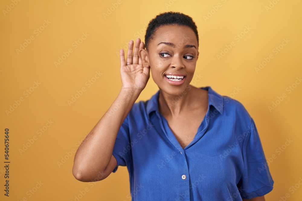 African american woman standing over yellow background smiling with ...