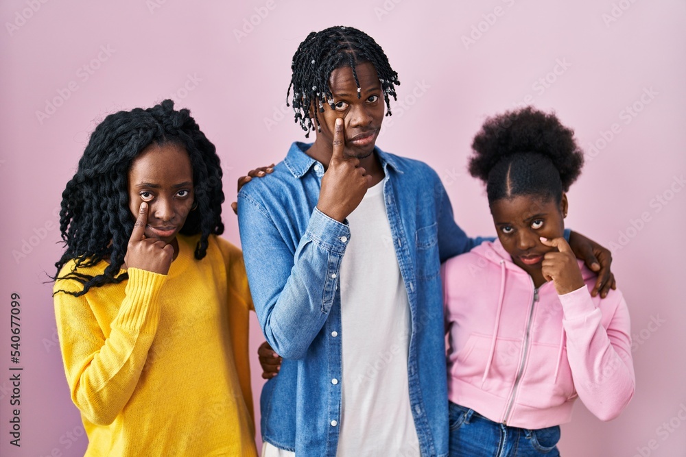 Group of three young black people standing together over pink ...