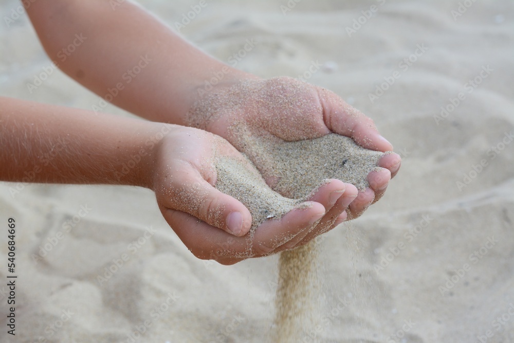 Child pouring sand from hands on beach, closeup. Fleeting time concept ...