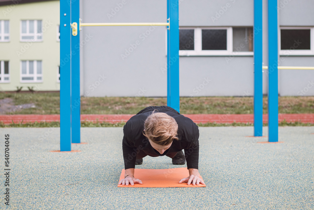Blonde athlete performs an exercise called a push-up. A heavy intense ...