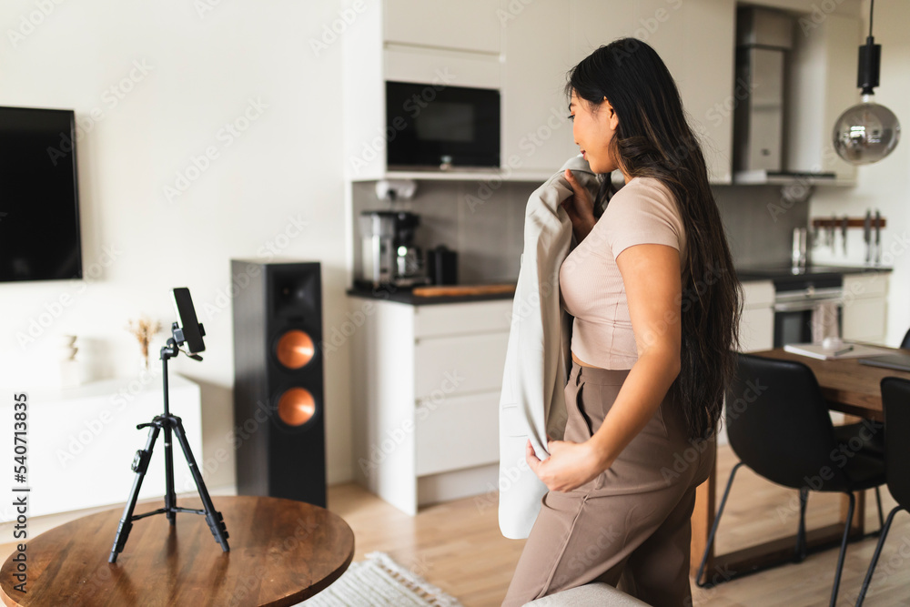 Young influencer showing blazer and vlogging through smart phone at home Stock Photo | Adobe Stock