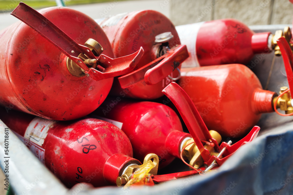 Many red fire extinguishers are lying in stack. Fire extinguishing ...