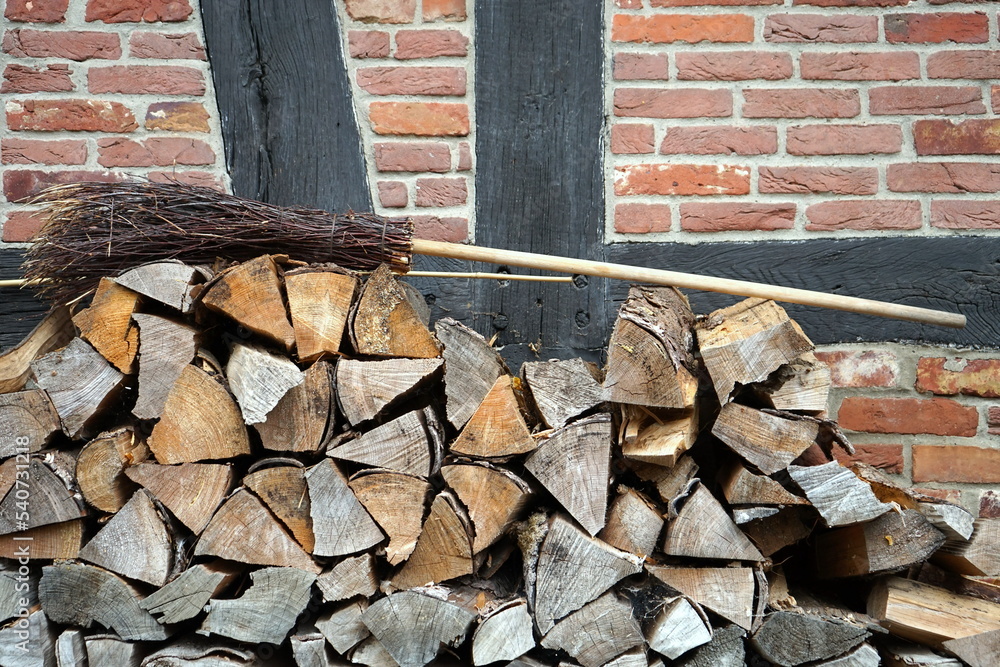 Holzstapel mit altem Brennholz und Besen aus Reisig vor Backstein des ...