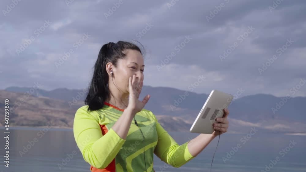a girl with a tablet on the background of mountains and a lake is ...