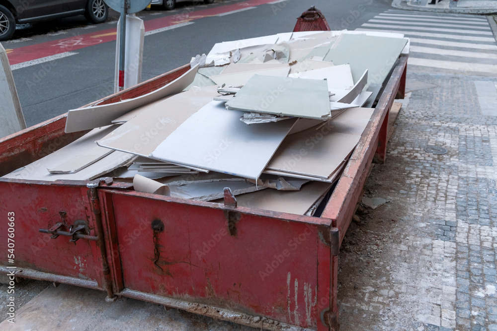 Heap of used drywall loaded in dumpster waste, metal red container ...