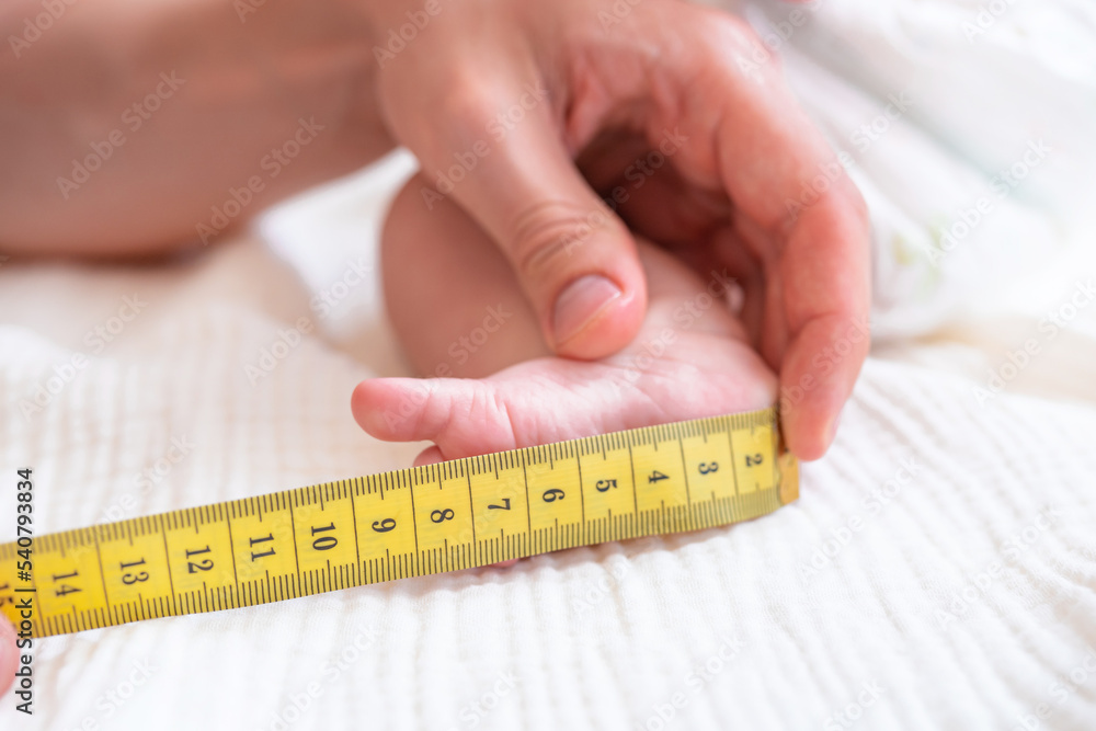 The baby's foot is measured with a measuring tape. choosing the size ...
