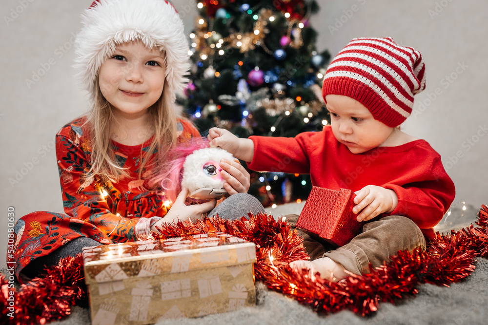 Children open Christmas gifts sitting at the Christmas tree Stock Photo ...