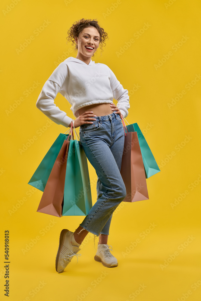 Front view of slim girl standing, holding packages, hands on waist ...