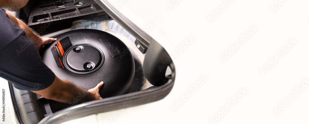 A mechanic is installing a car circle-shaped LPG tank in a spare wheel ...